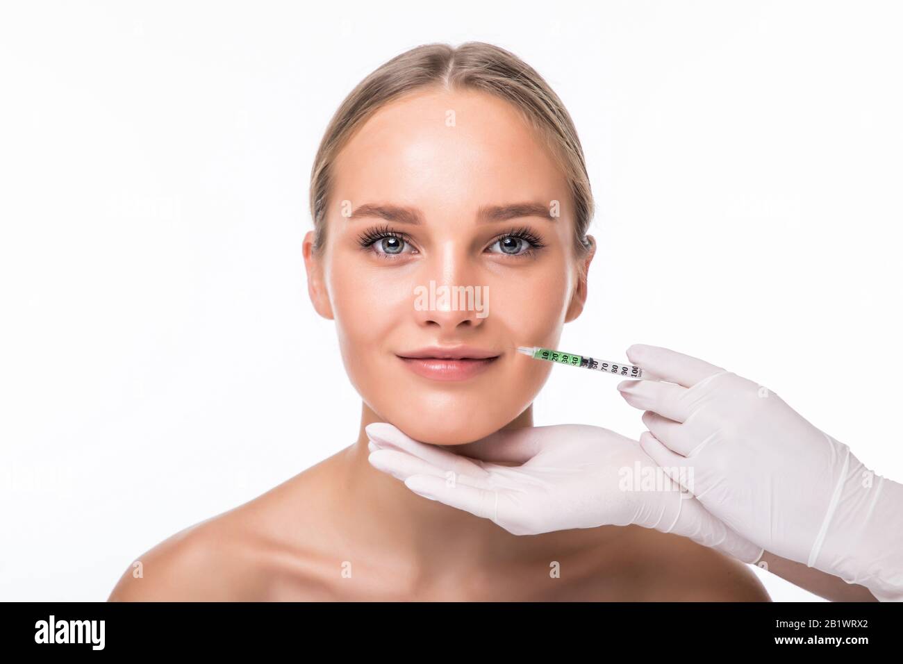 Closeup of beautiful woman gets injection in her lips. Isolated over ...