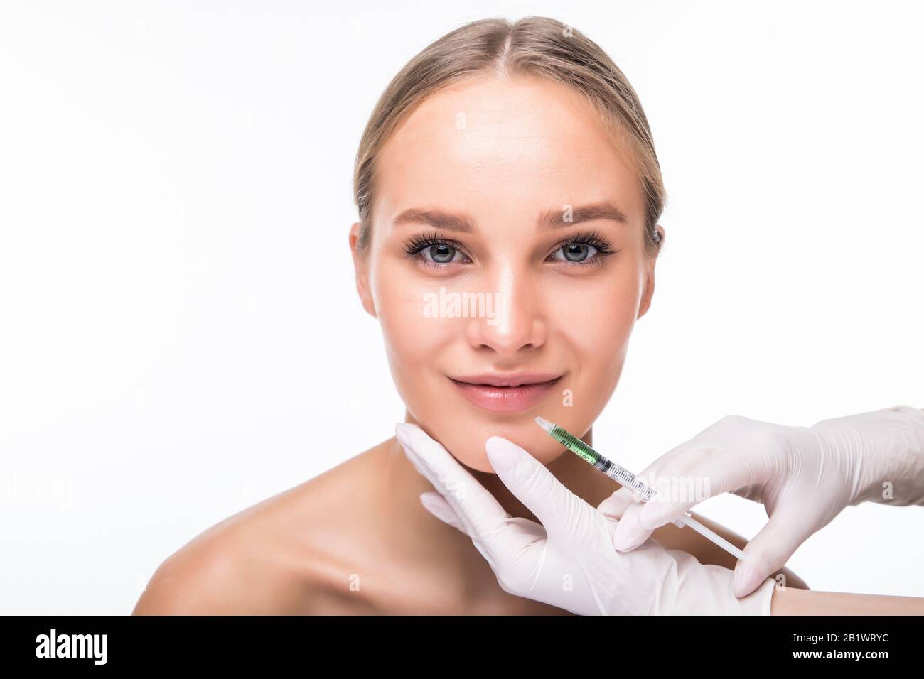 Closeup of beautiful woman gets injection in her lips. Isolated over ...