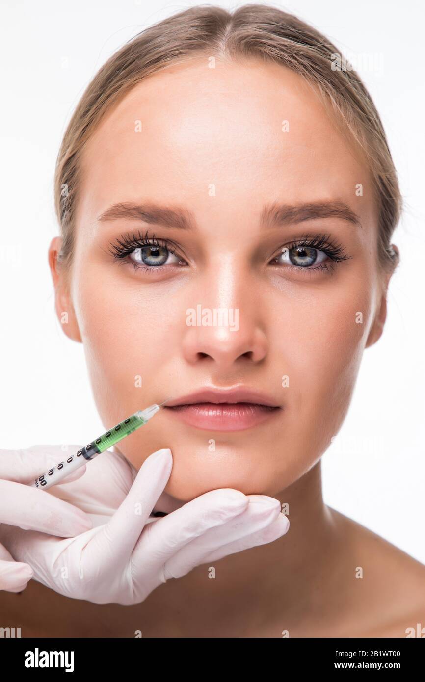 Close up of hands of cosmetologist making botox injection in female lips. The young beautiful ...