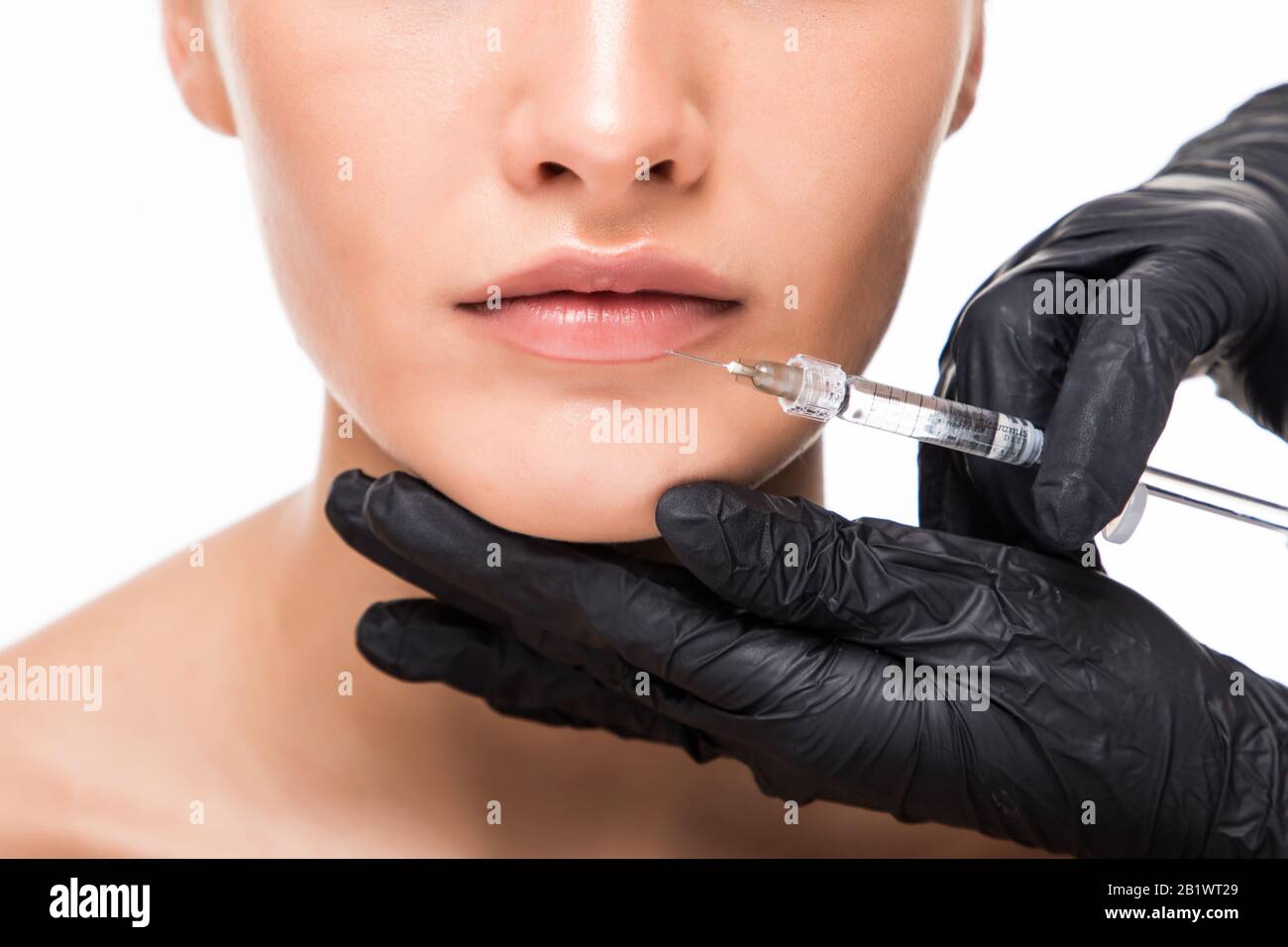 Closeup of beautiful woman gets injection in her lips. Isolated over ...