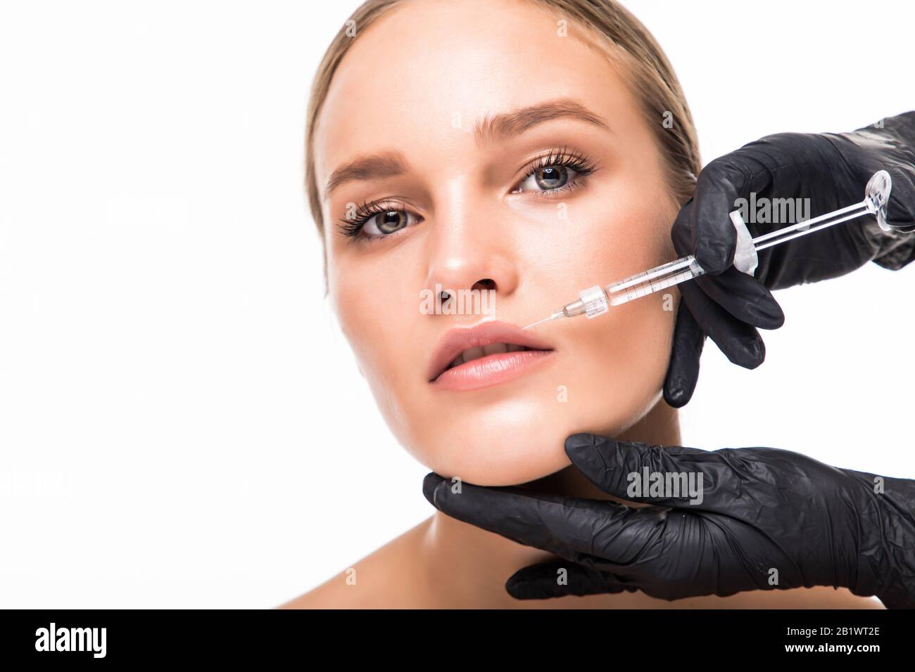 Closeup of beautiful woman gets injection in her lips. Isolated over ...