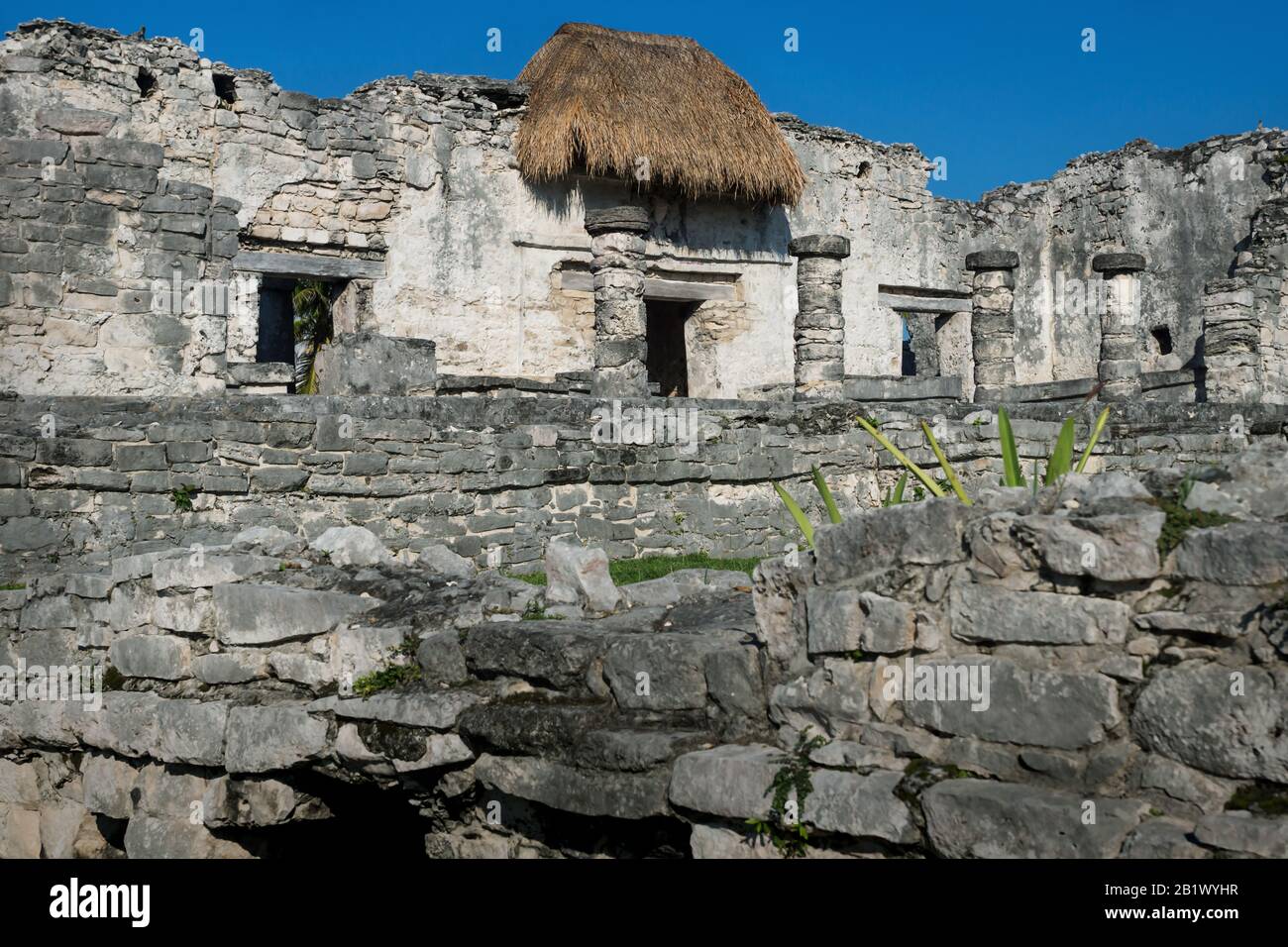 Maya ruins with straw roof behind blurred wall and blue sky, Tulum ...