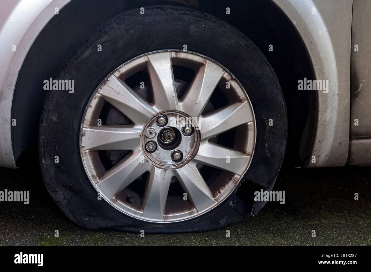A large hole in the wall of a tyre after a blowout. The rim of the ...