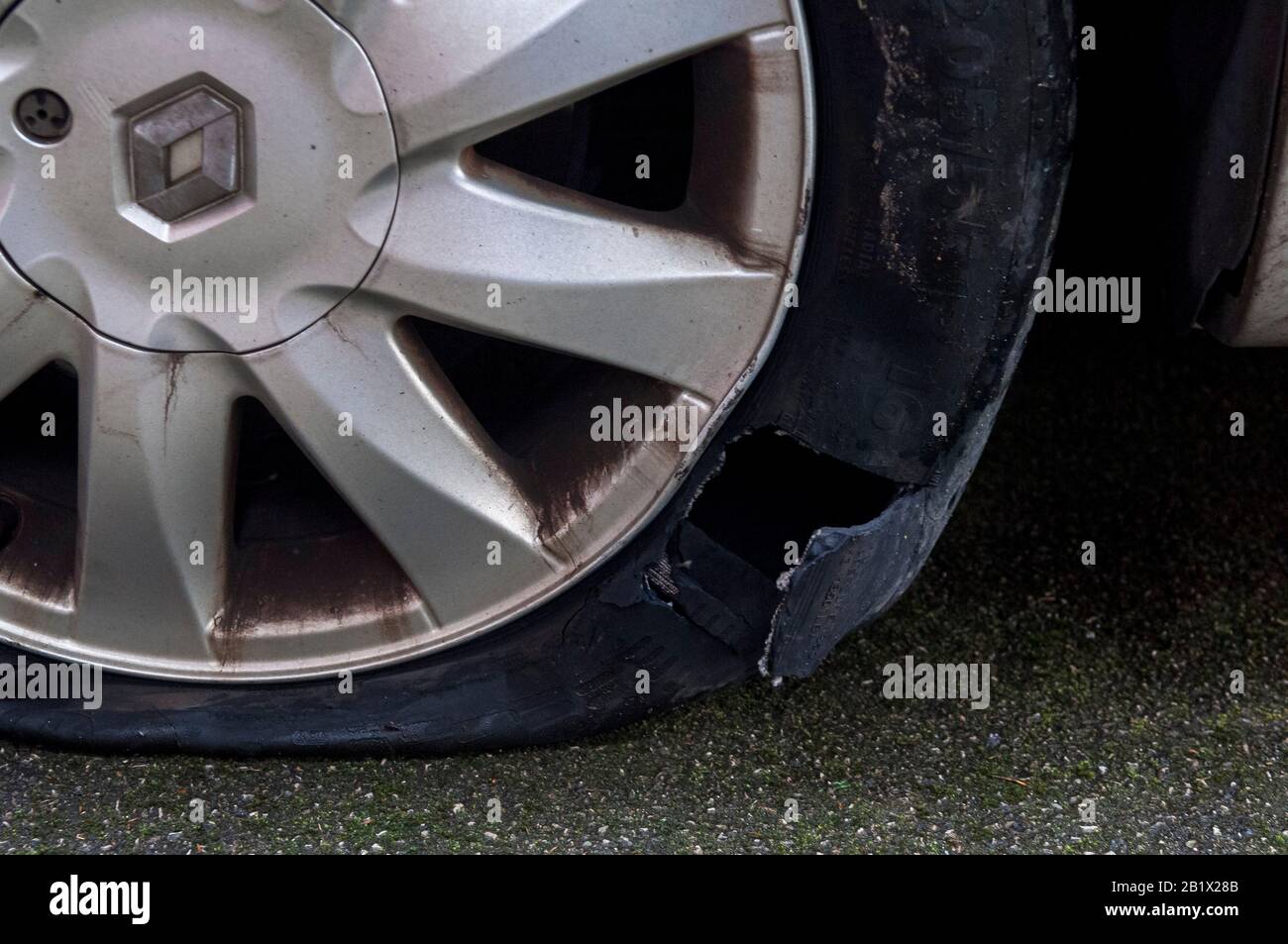 A large hole in the wall of a tyre after a blowout. The rim of the ...