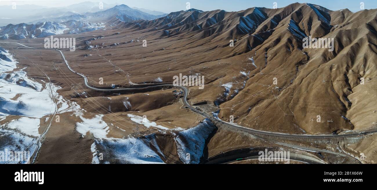 The country road winding through a valley surrounded by snowy mountains ...