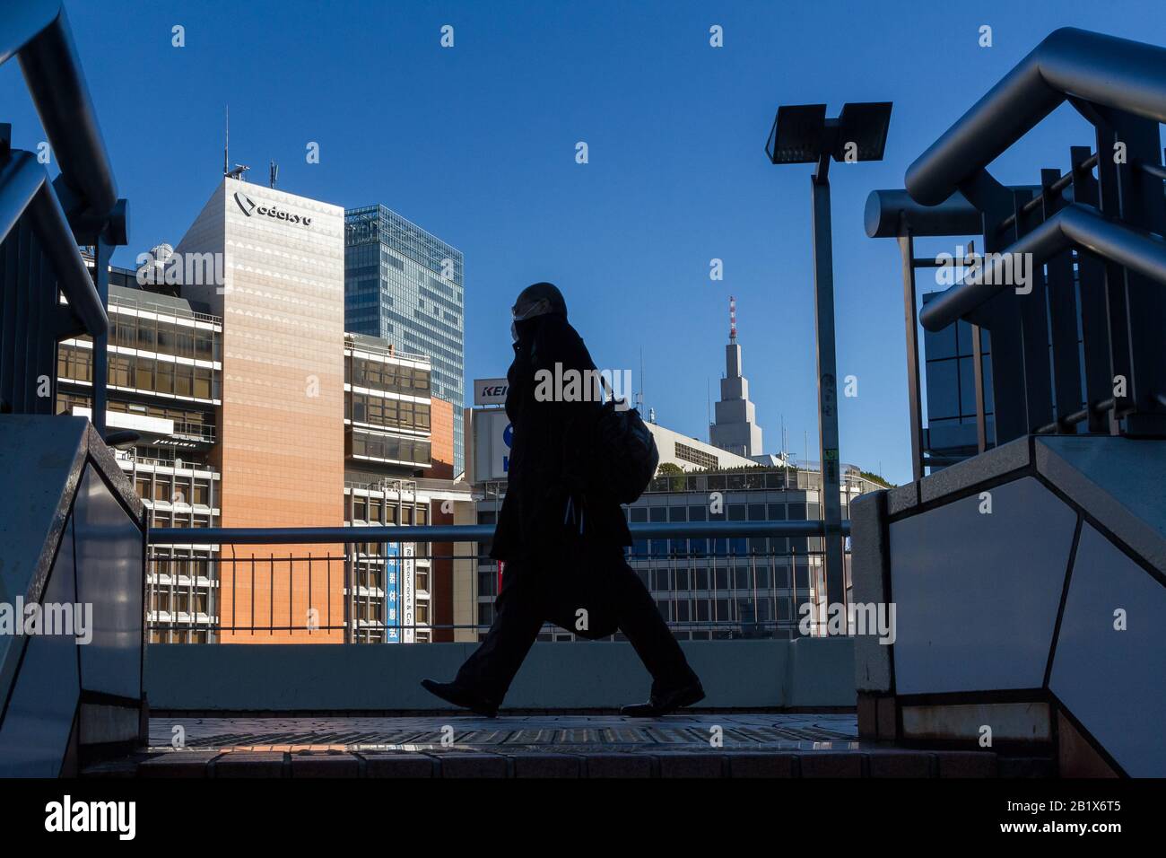 A Japanese salaryman or office worker walks on a pedestrian bridge near ...