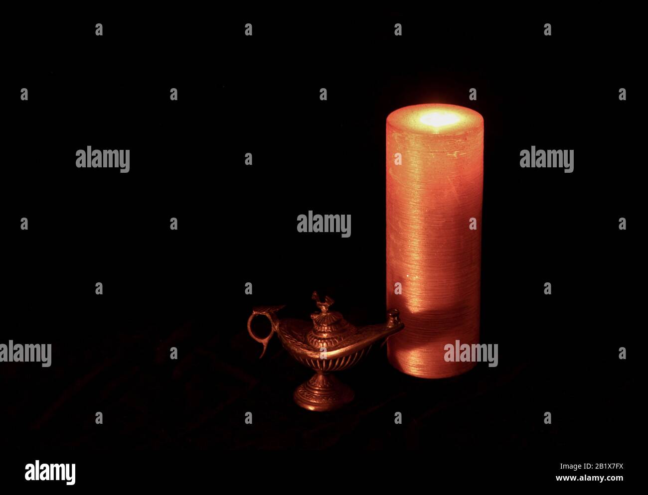 A brass genie lamp reflections upon a sparkly gold holiday candle to ...