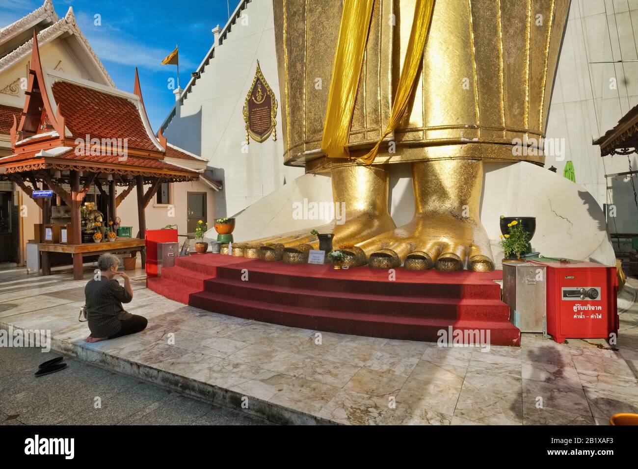 A Buddhist woman prays in front of the feet of the 32 m high golden ...