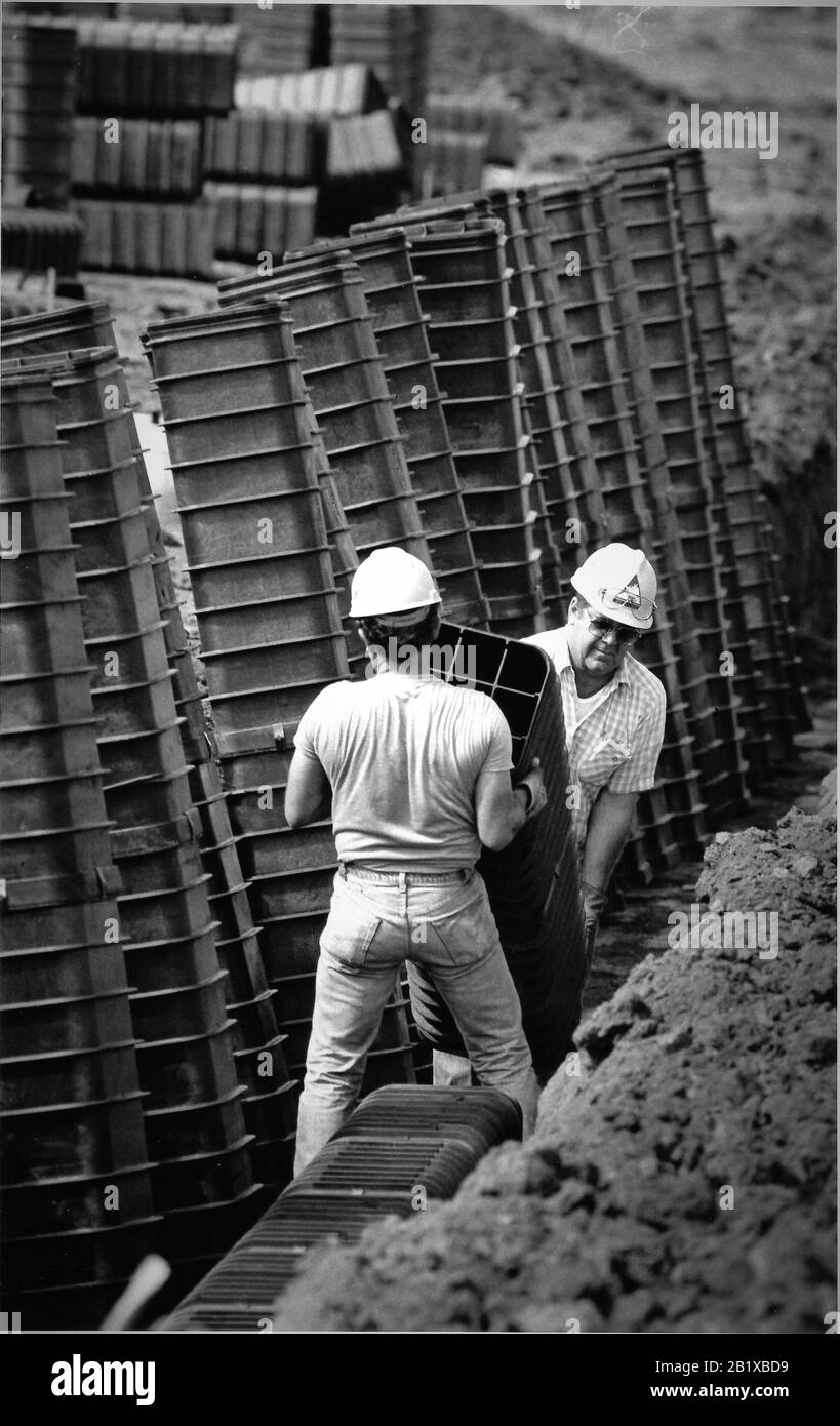 Workmen installing multi sectional real pipes for running cables for ...