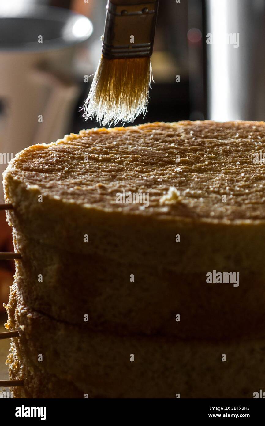 close up of a brush cleaning up crumbs from a fresh baked vanilla cake ...