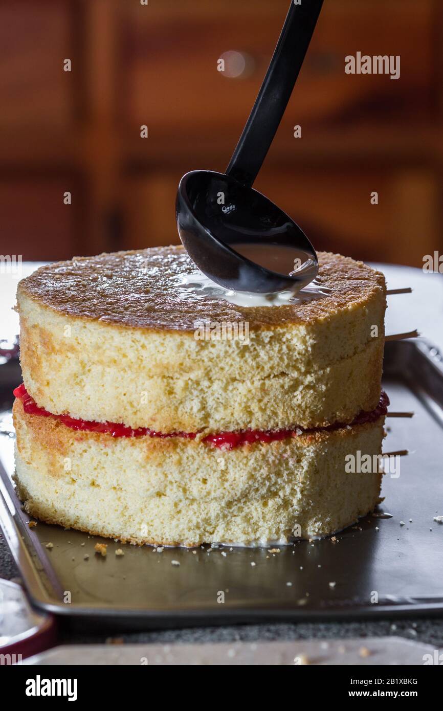 adding moisture to the top layer of a strawberry vanilla cake Stock ...