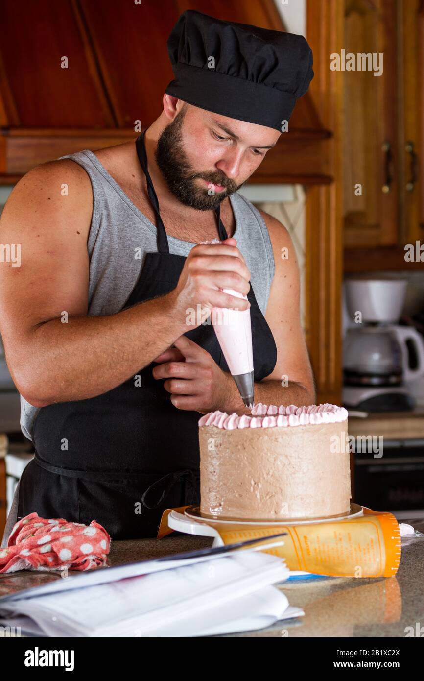 male baker decorating a chocolate birthday cake with strawberry moose ...