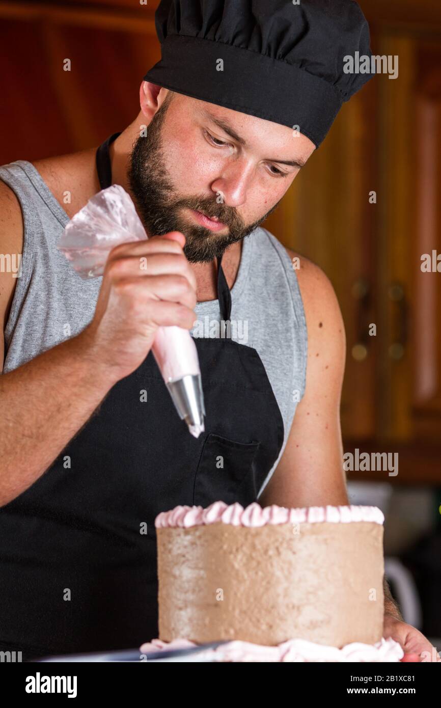 male baker decorating a chocolate birthday cake with strawberry moose ...