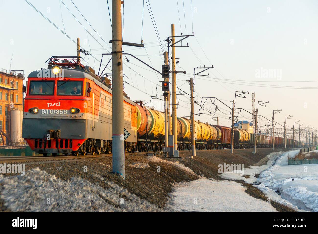 red locomotive of Russian Railways carries a freight train with tanks ...