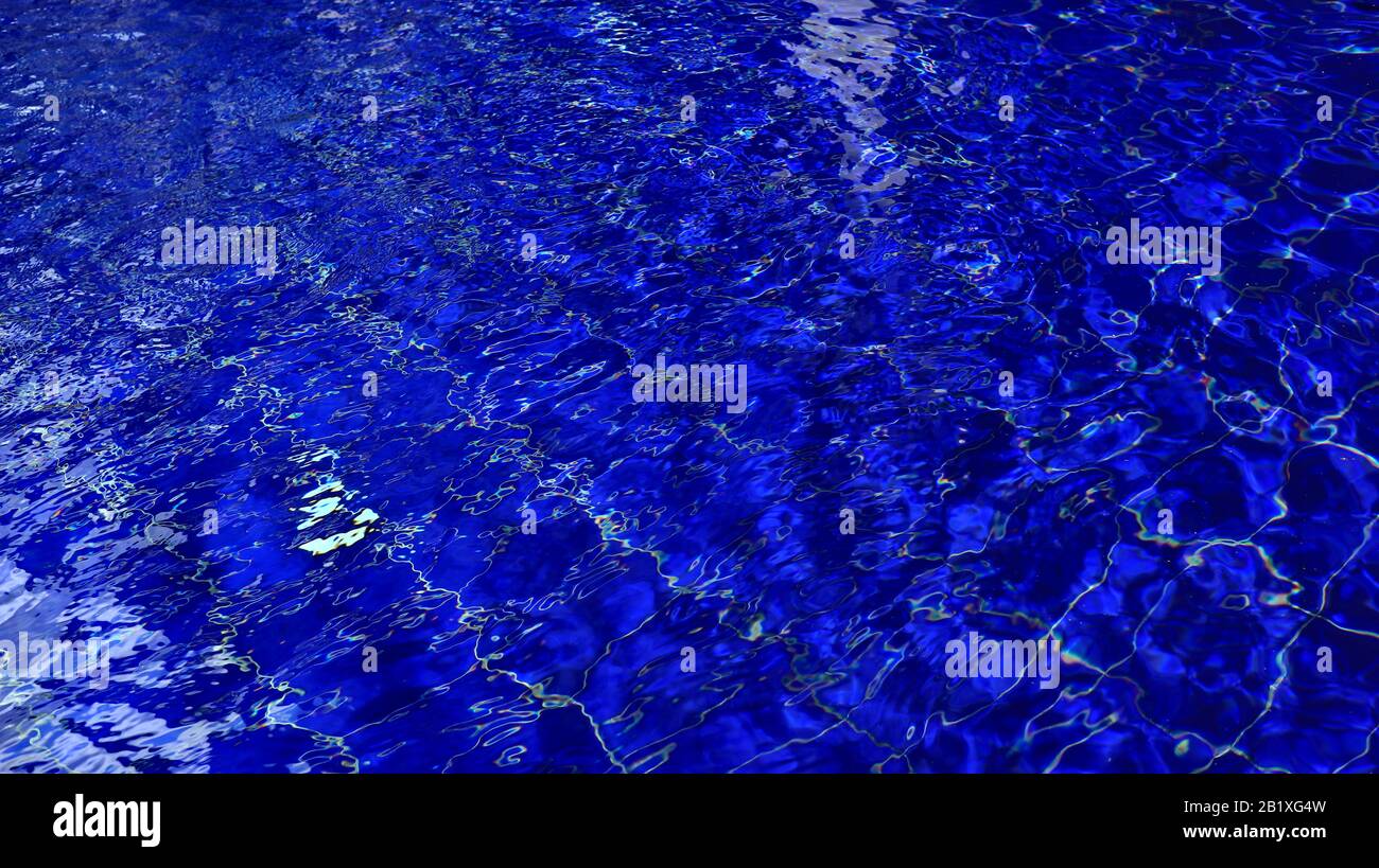 Background of swimming poll water with ripple and sun reflections on a ...