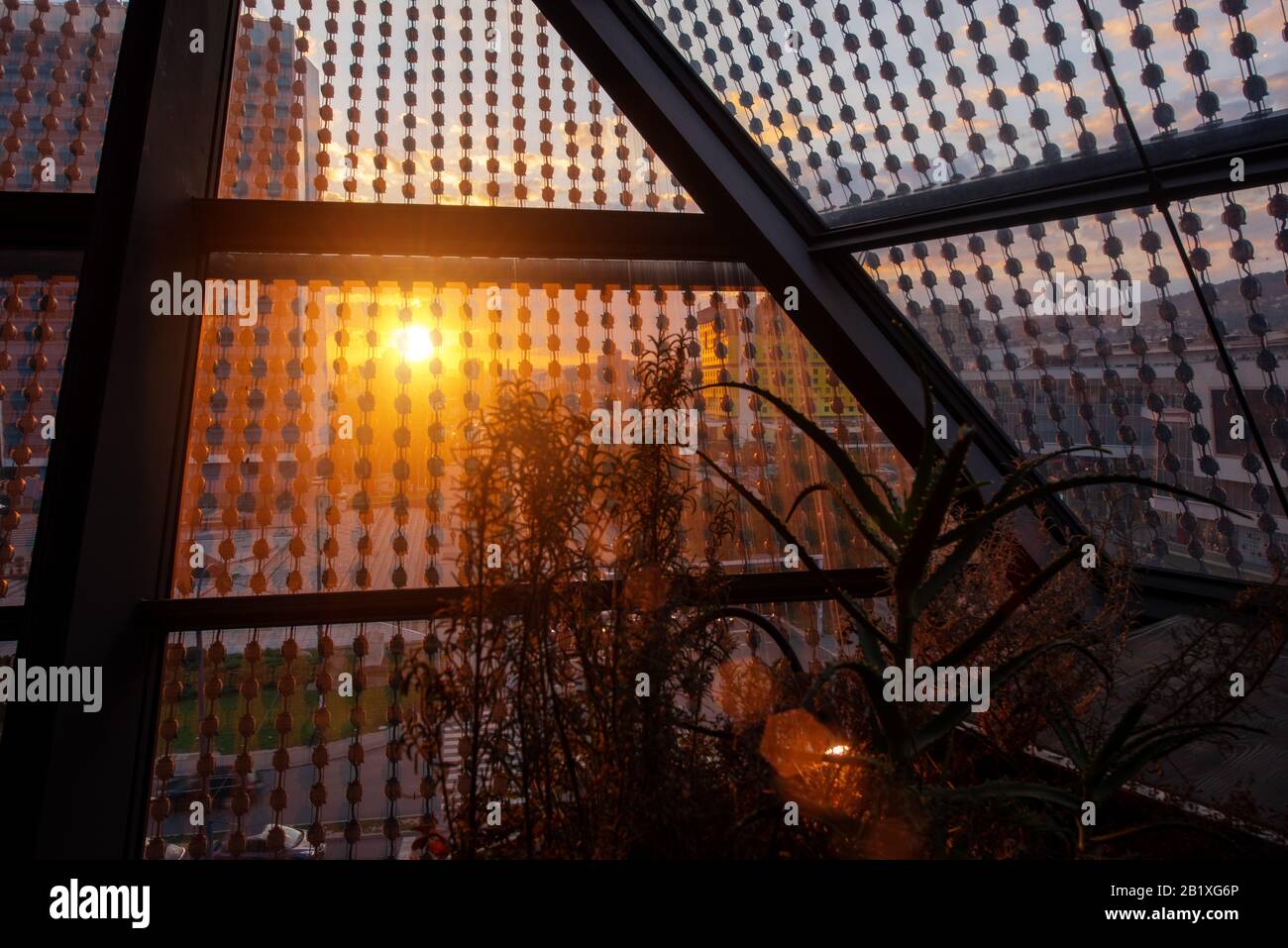 sunset or sunrise above the city through a glass roof in a modern ...