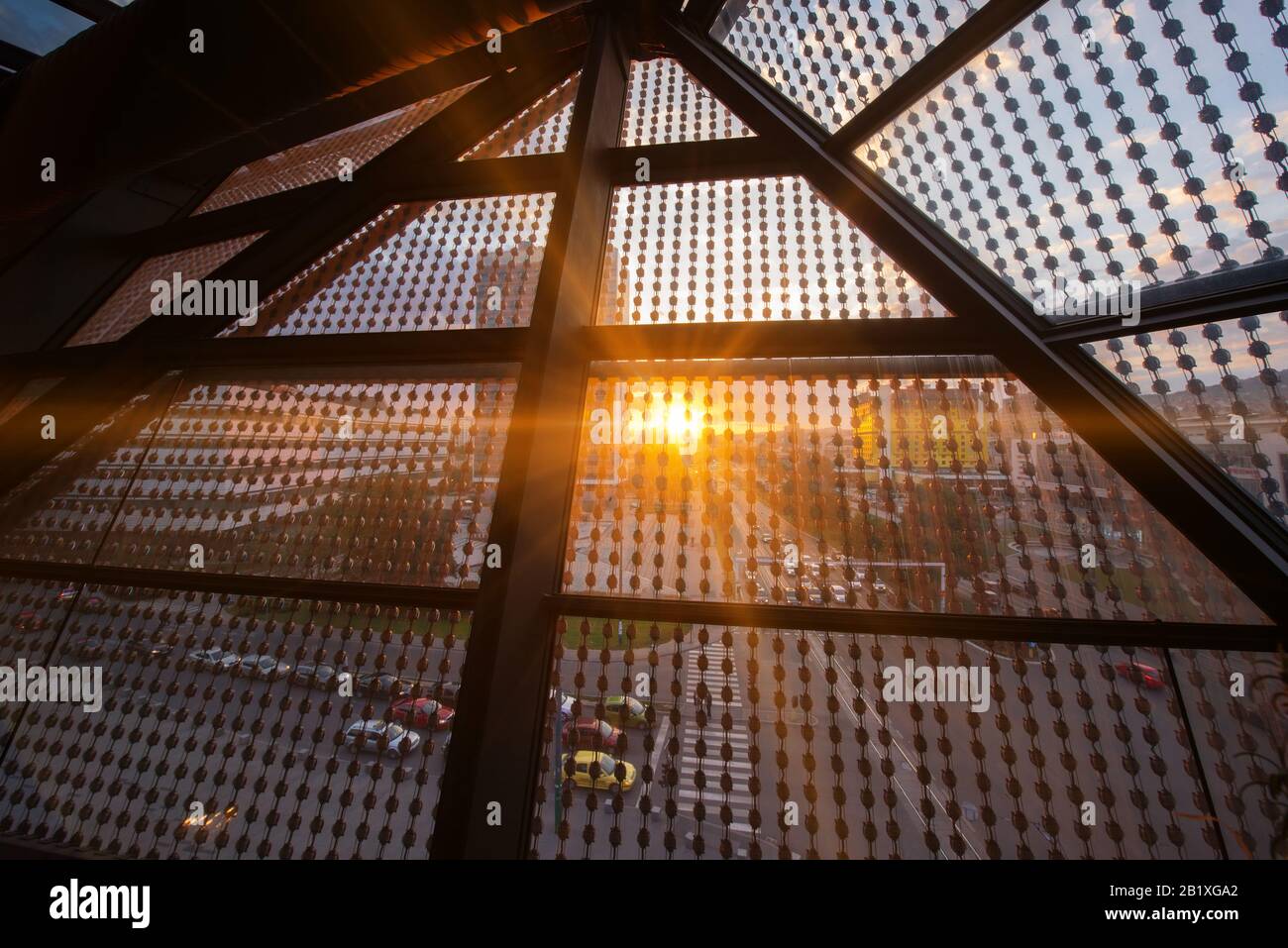 sunset or sunrise above the city through a glass roof in a modern ...