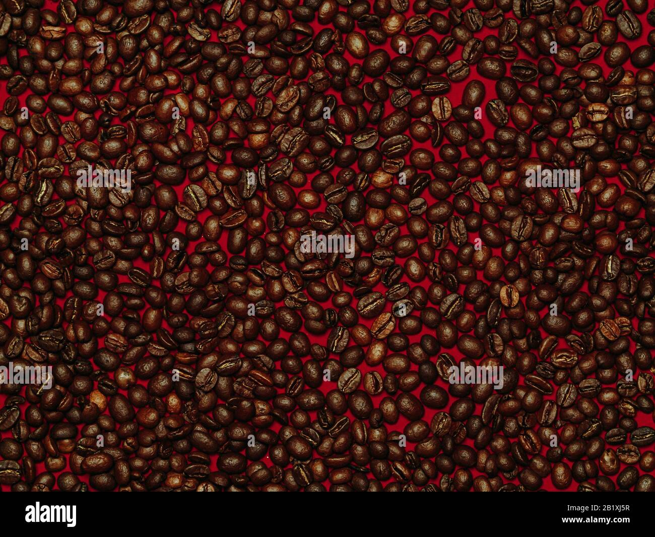 Roasted coffee beans on red background Stock Photo - Alamy
