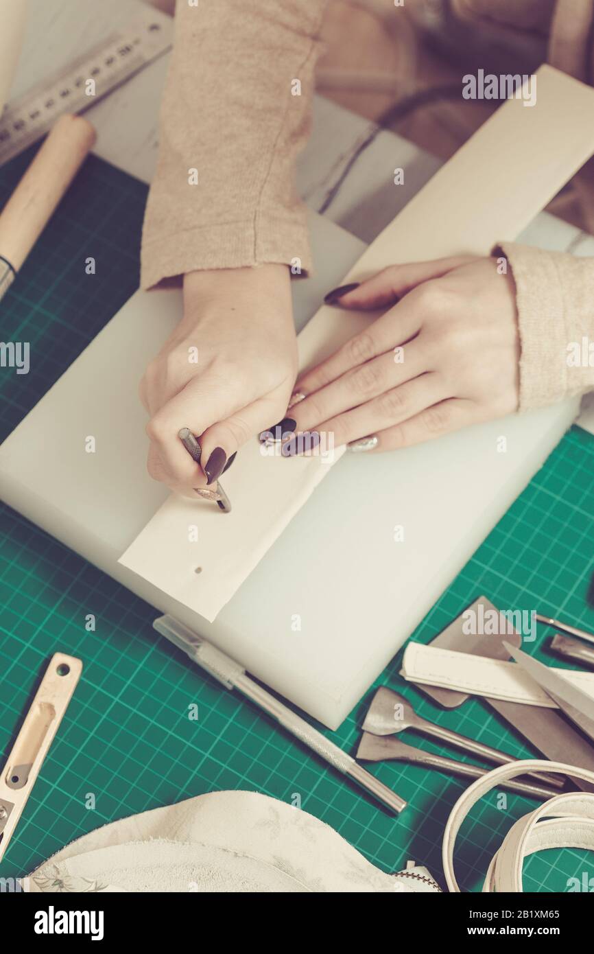 Close up of woman hands working with natural leather using hammer ...