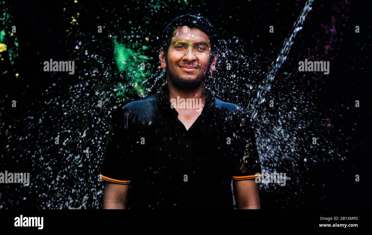 Young man playing holi with water. water splashing on his face. holi is ...