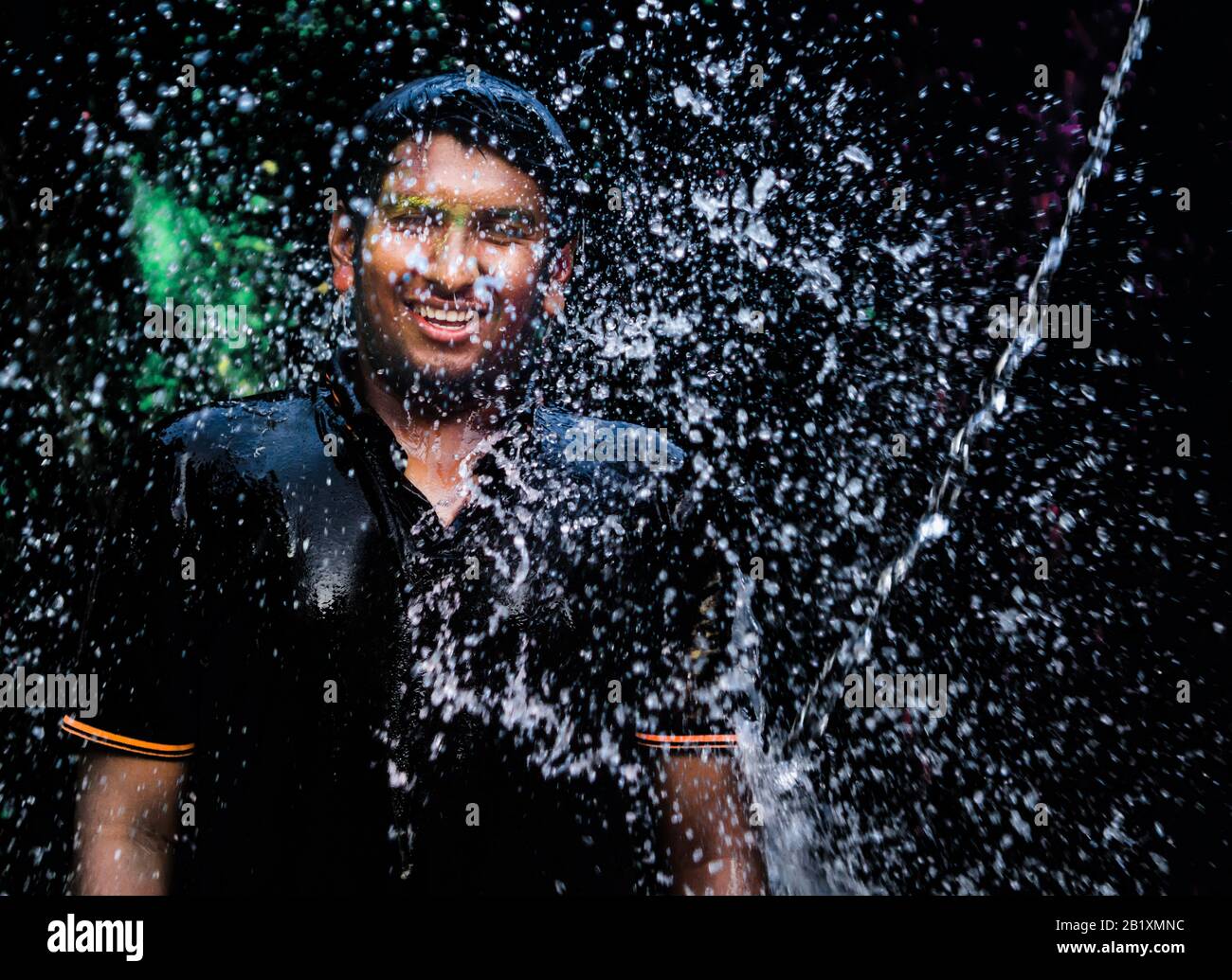 Young man playing holi with water. water splashing on his face. holi is ...