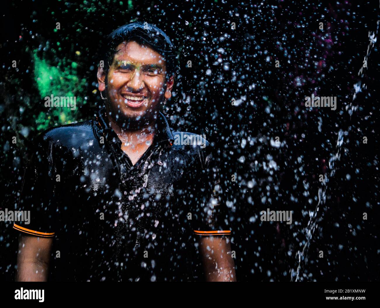 Young man playing holi with water. water splashing on his face. holi is ...