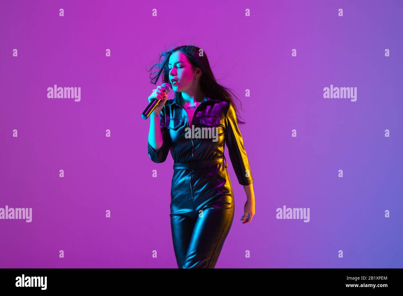 Caucasian female singer portrait isolated on purple studio background ...