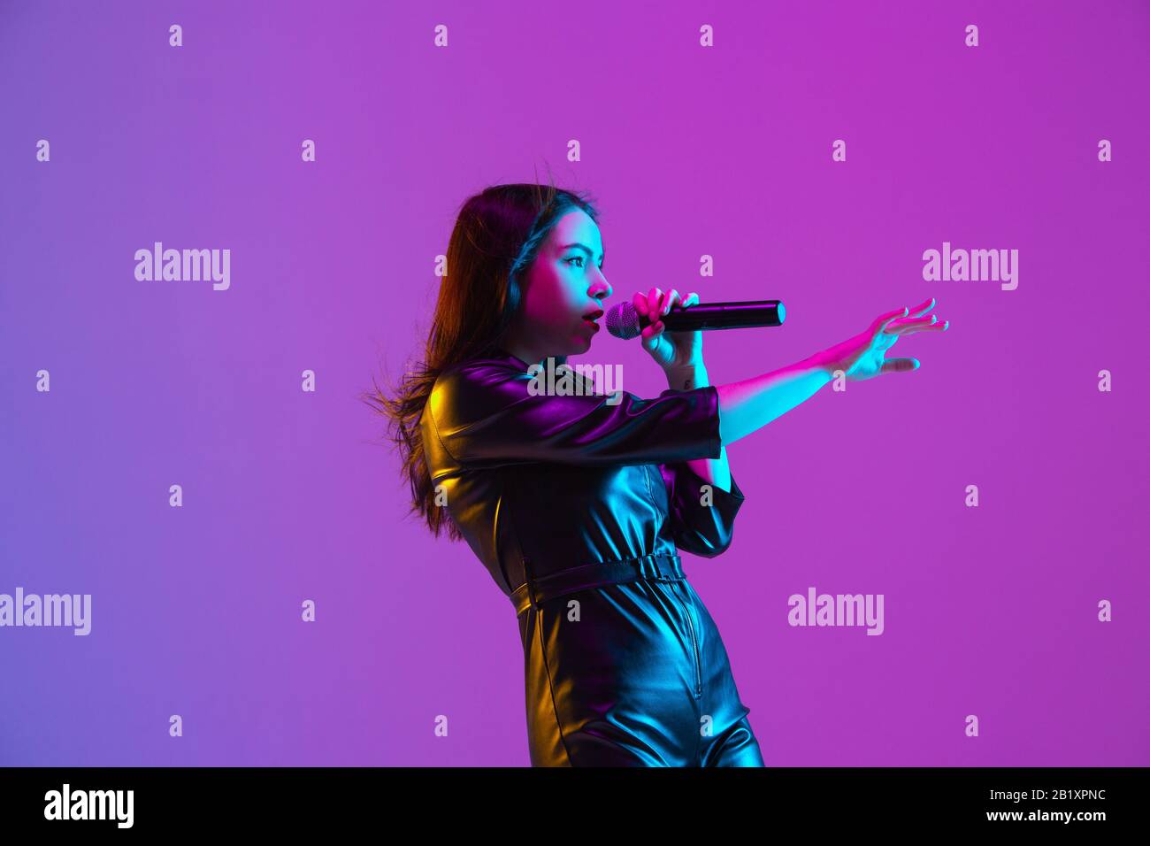 Caucasian female singer portrait isolated on purple studio background ...