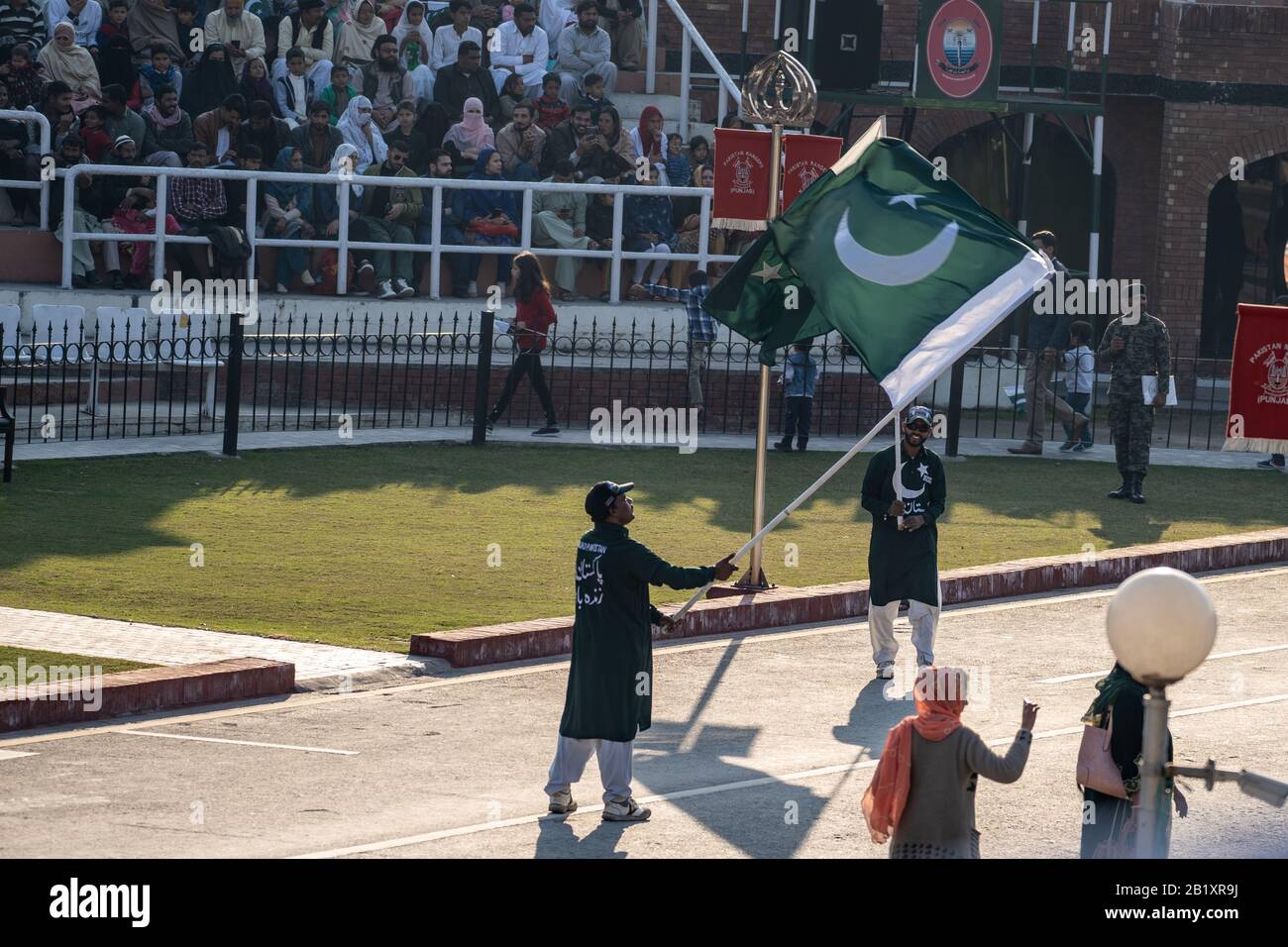 Wagah, Pakistan - Febuary 8, 2020: Two Pakistani men wave flags and ...