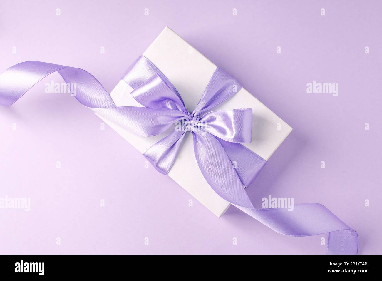 Craft gift box on a lilac background, decorated with a textured bow and ...