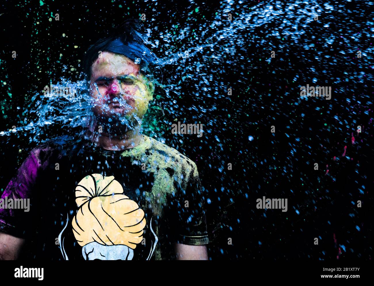 Young man playing holi with water. water splashing on his face. holi is ...