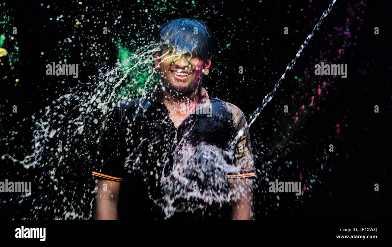 Young man playing holi with water. water splashing on his face. holi is ...