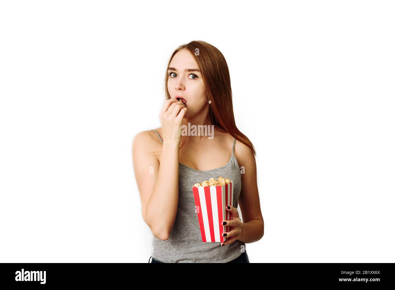 An interested girl watching a movie and eating popcorn on a white ...
