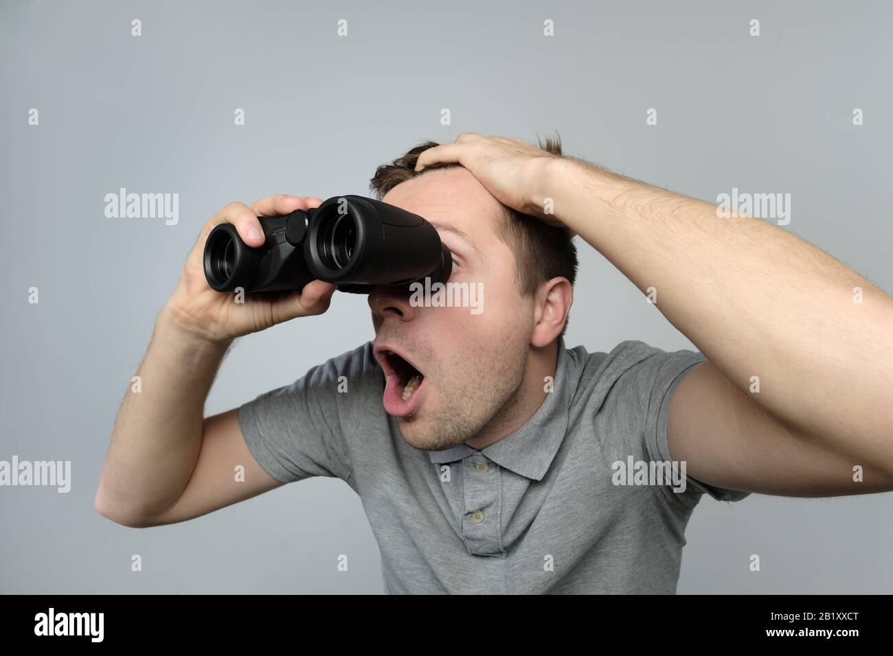 Young shocked man looking to the future through binoculars against a ...