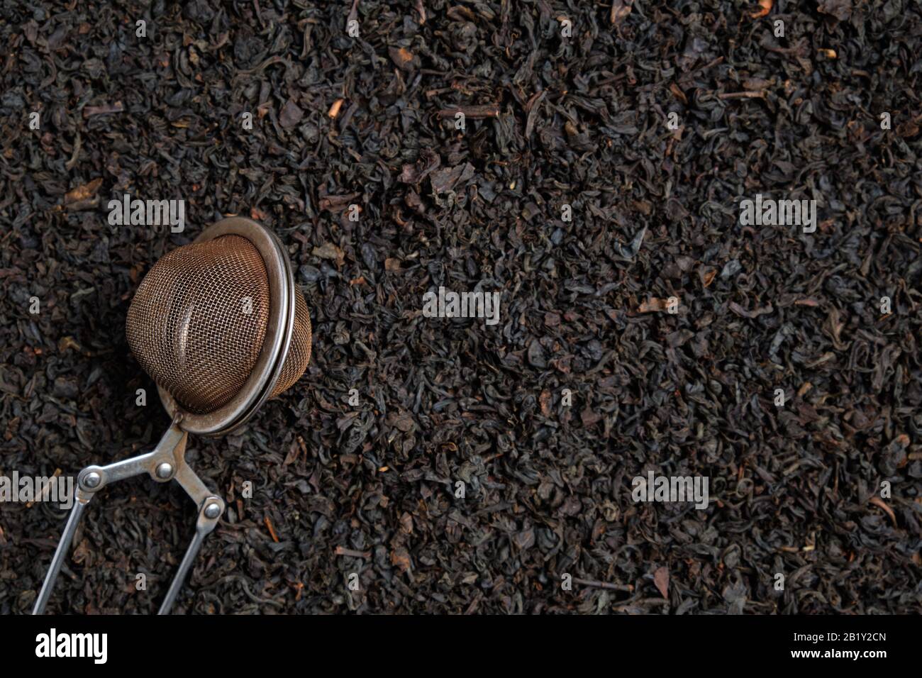 Metal brewing tool on black tea background with copy space. Close up ...