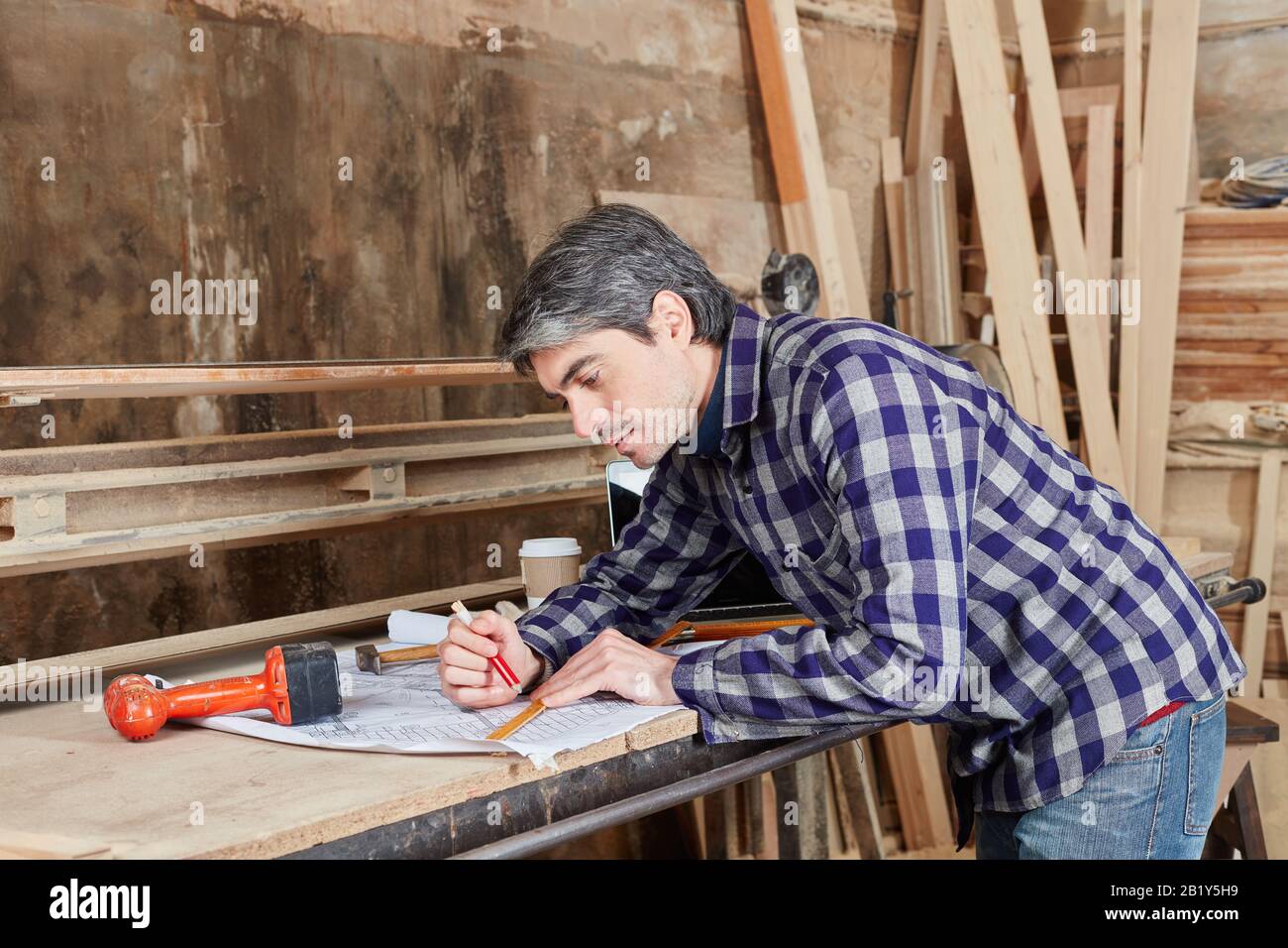 Carpenter works with blueprint in a workshop Stock Photo - Alamy