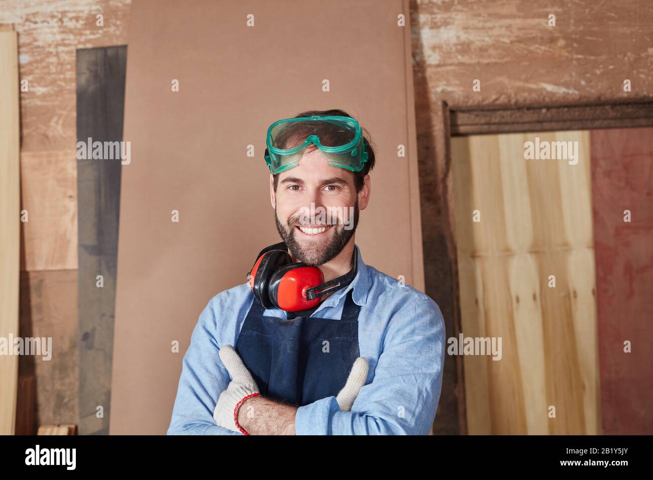 Satisfied carpenter smiles in workshop with crossed arms Stock Photo ...