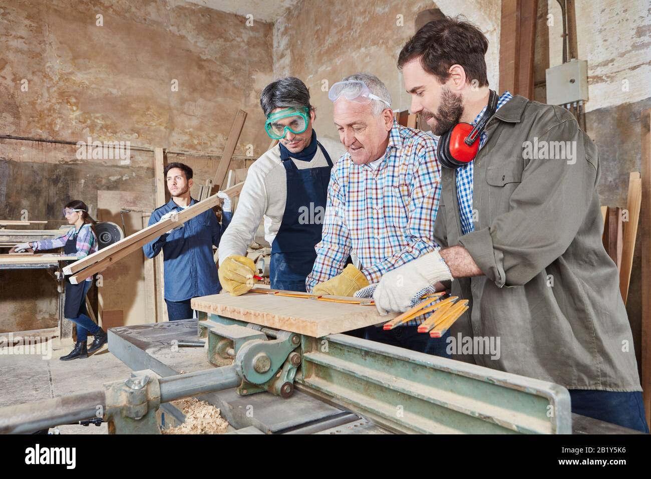 Carpenters work together in carpentry in front of a planing machine ...