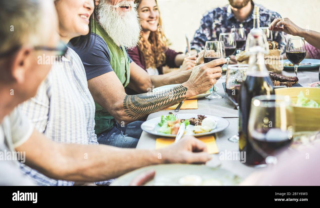 Happy family eating and drinking wine at barbecue dinner on patio ...