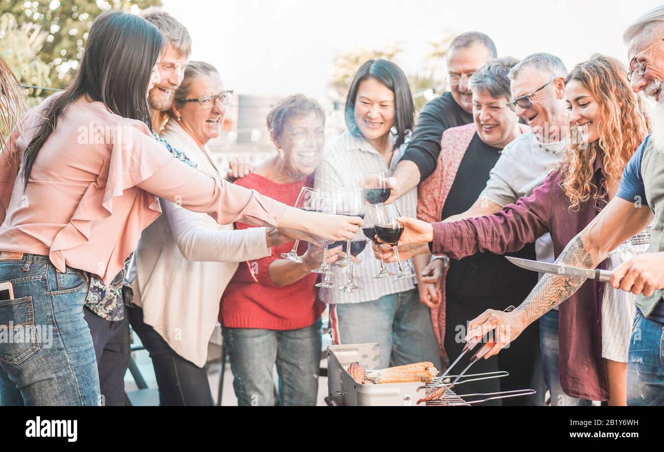 Family grilling meat and cheering with red wine at bbq meal outdoor ...