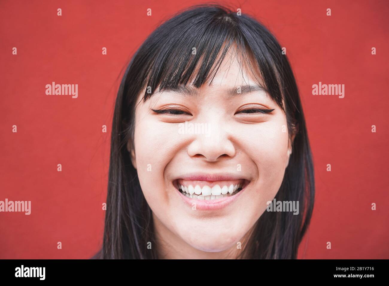 Portrait of happy asian girl smiling with red background - Young ...