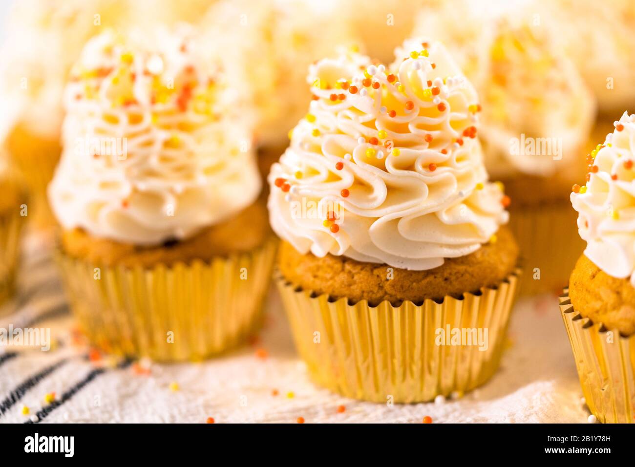 Decorating pumpkin spice cupcake with Italian buttercream and sprinkles ...
