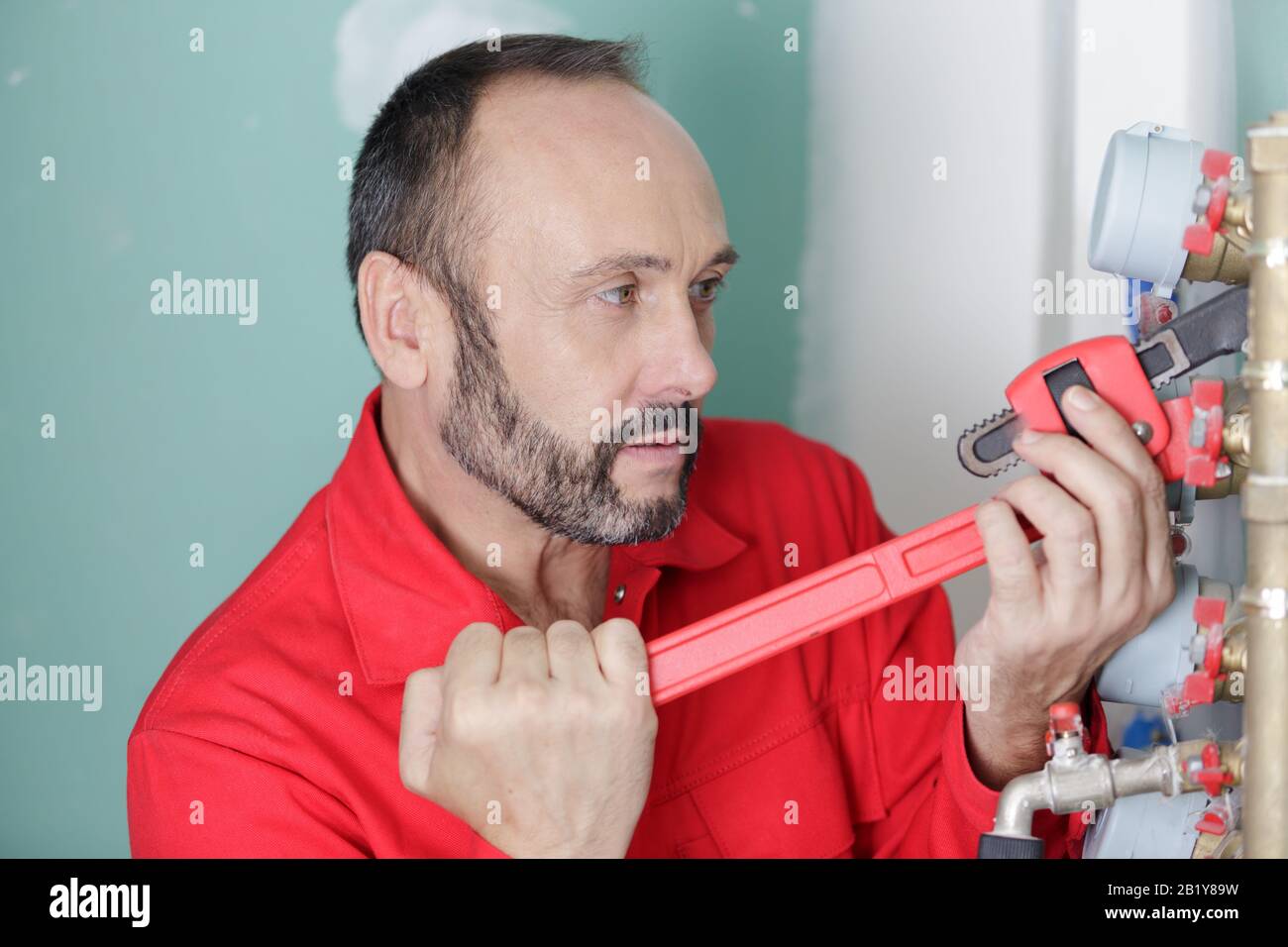 plumber with tool in hand is repairing a pipe Stock Photo - Alamy