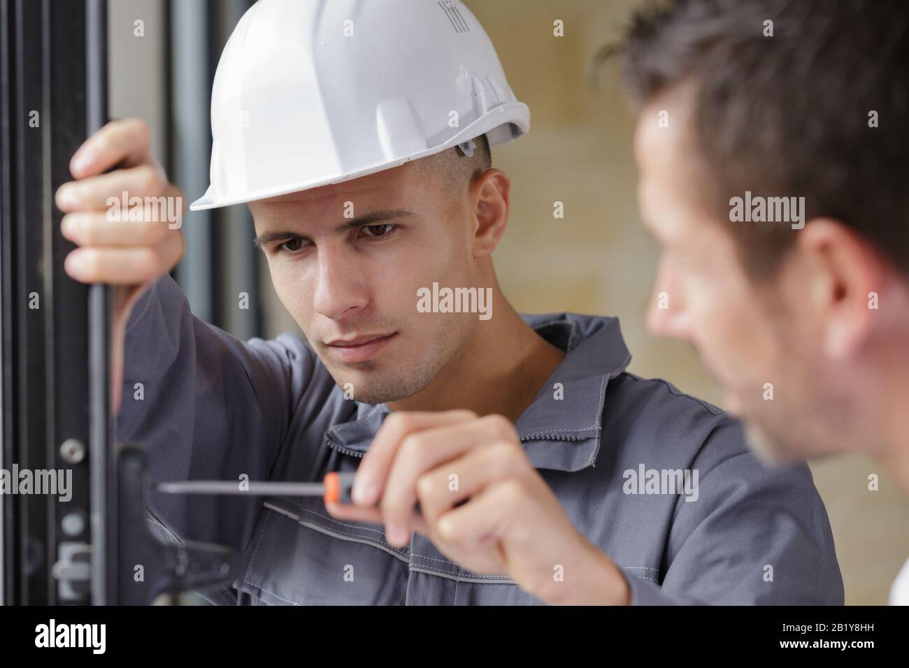 repairman fixing window with screwdriver Stock Photo - Alamy