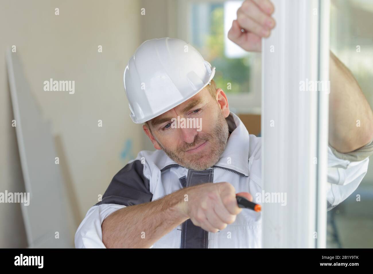 seniro man fitting a pvc window Stock Photo - Alamy