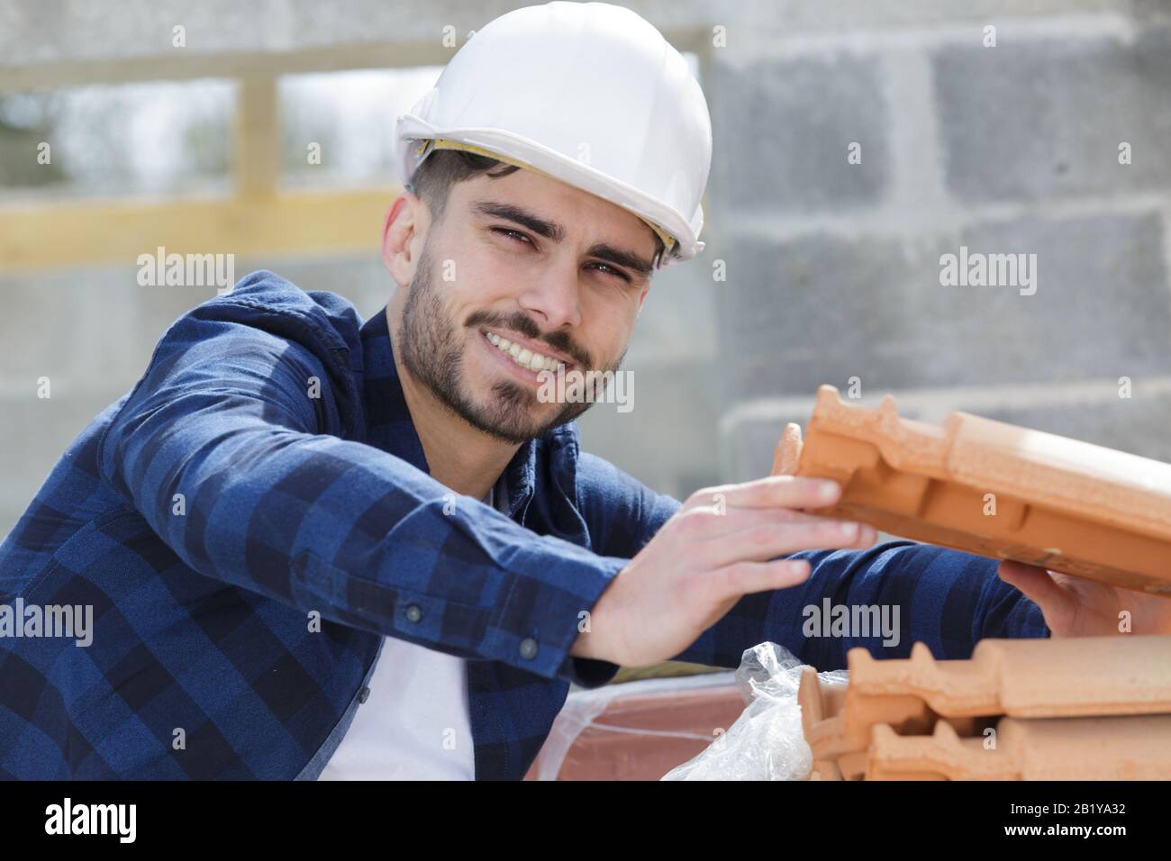 portrait of builder lifting roof tiles Stock Photo - Alamy