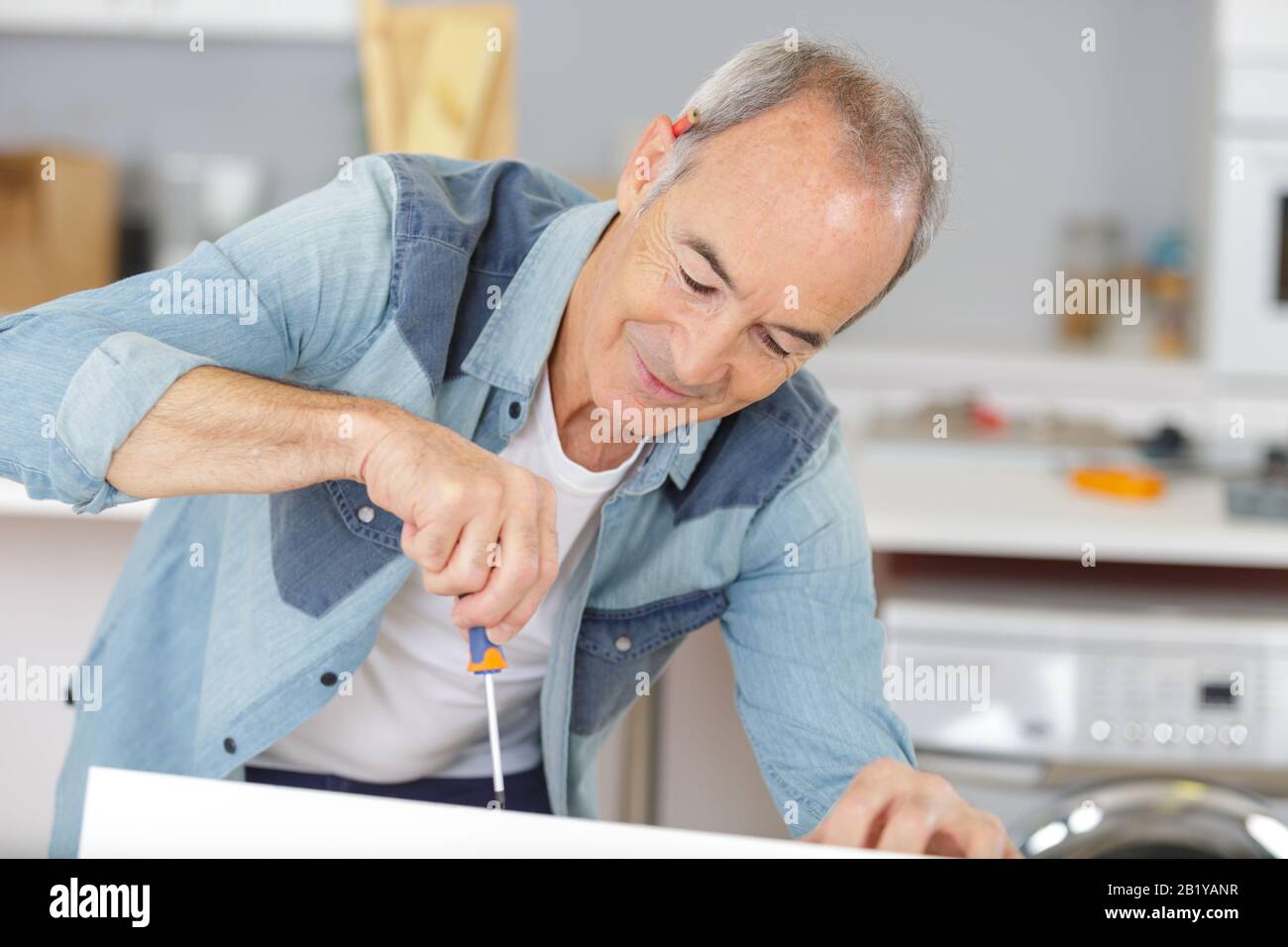 senior man using screwdriver in the kitchen Stock Photo - Alamy