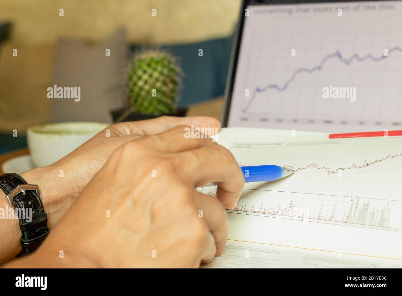 Businessman pointing on data chart with pen while working iwith laptop ...