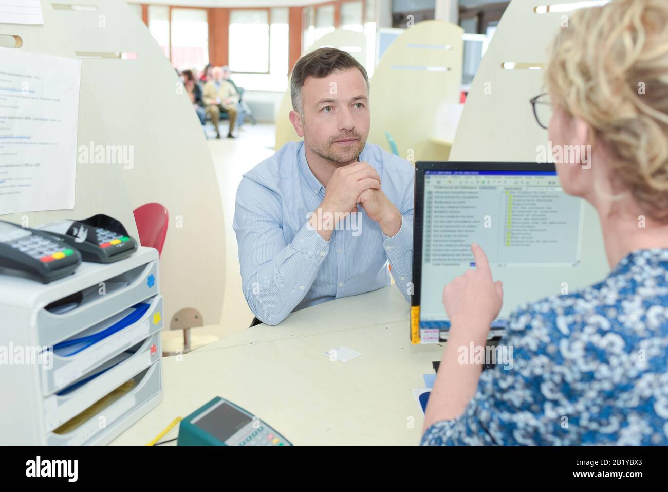patient sat at receptionists booth in hospital Stock Photo - Alamy