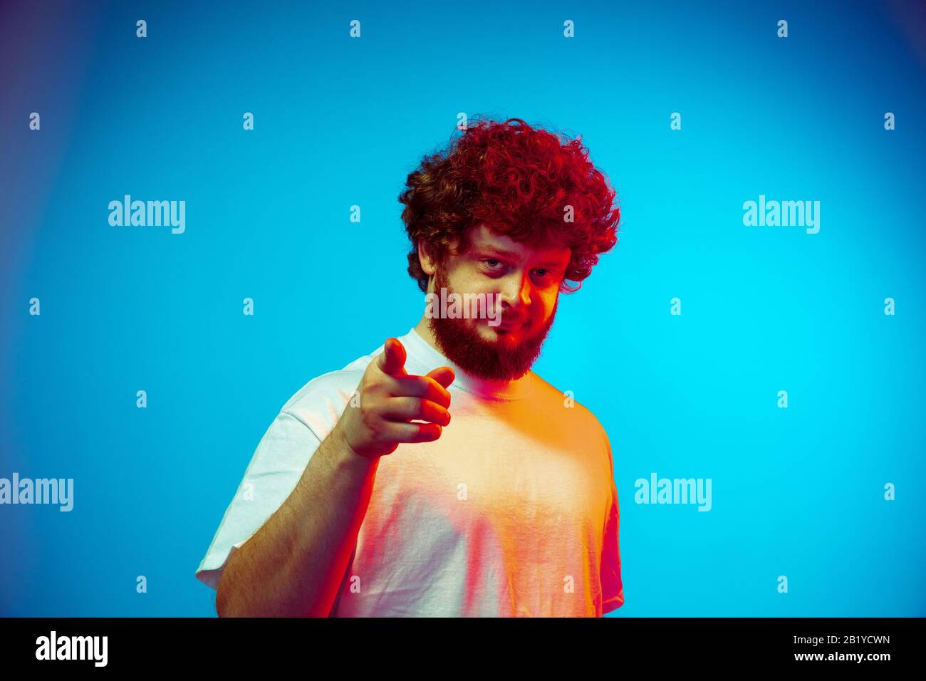 Pointing, choosing. Caucasian man's portrait isolated on blue studio ...